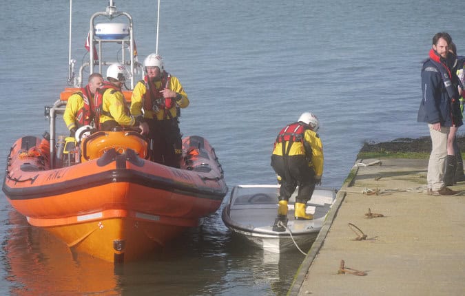 Damaged and waterlogged speedboat towed to safety by lifeboat